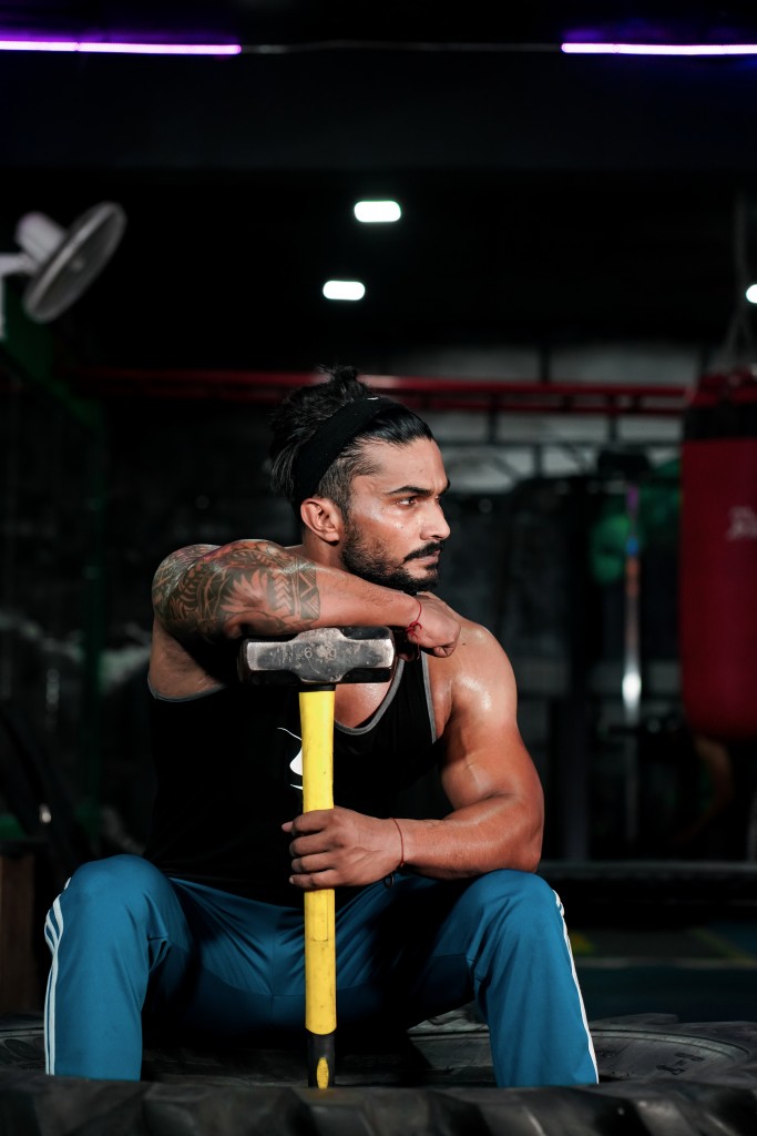 Big muscle man with hammer on tyre in Gym - PixaHive