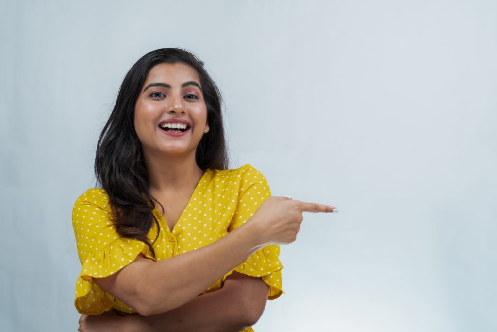 Happy young girl pointing sideways - PixaHive