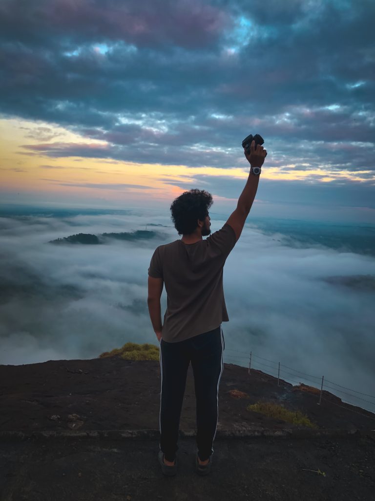 Man holding a camera at the peak - PixaHive