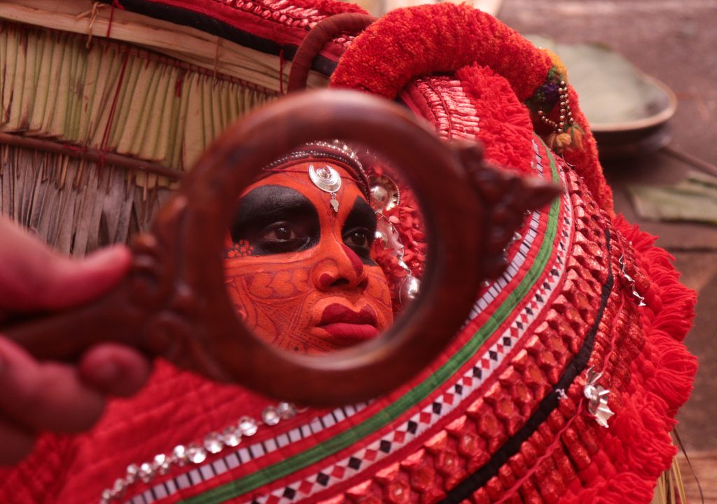 Vishnumoorthy Theyyam face makeup reflected in mirror - PixaHive