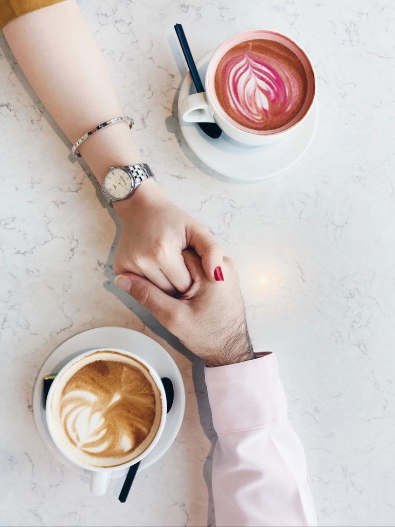 Couple holding hands over coffee - PixaHive