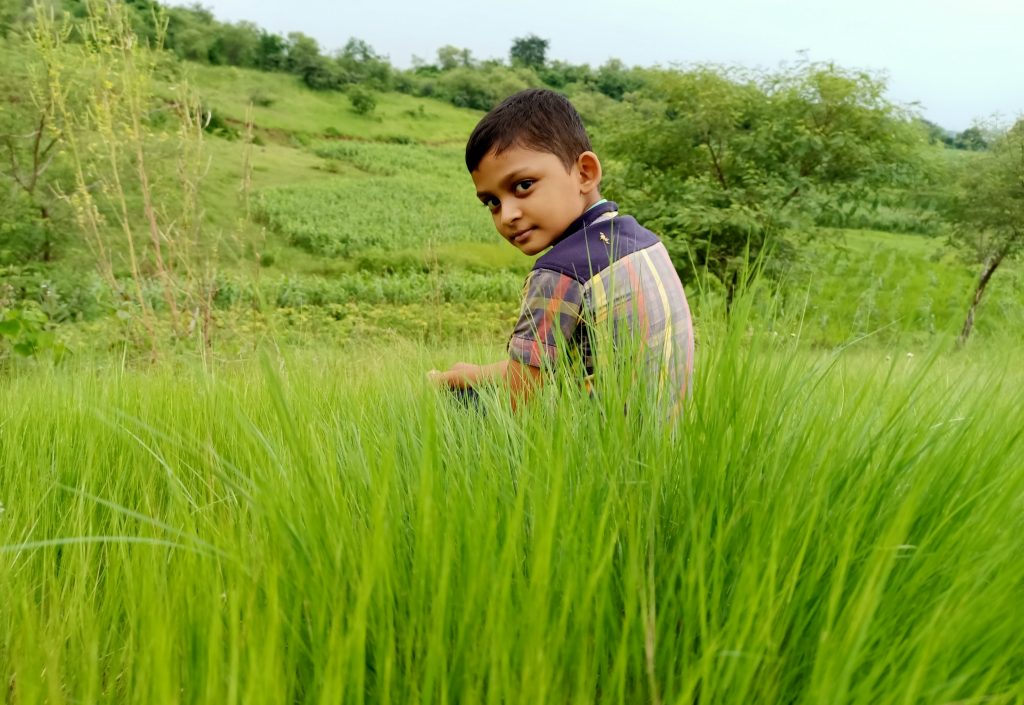 A boy sitting in grass - PixaHive