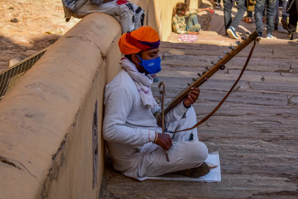 Boy with mask playing music instrument roadside - PixaHive